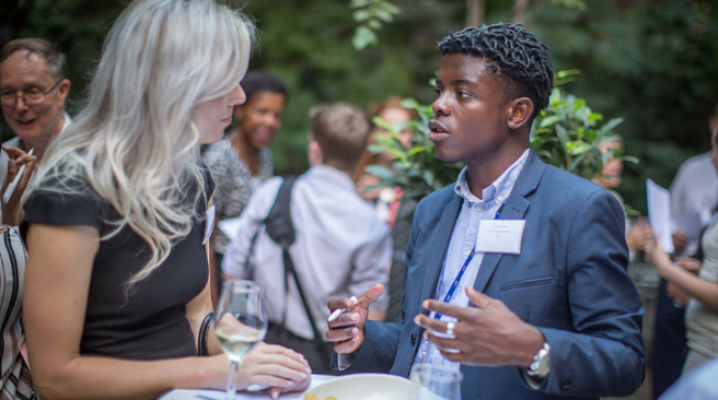 Young man speaks to woman at networking event